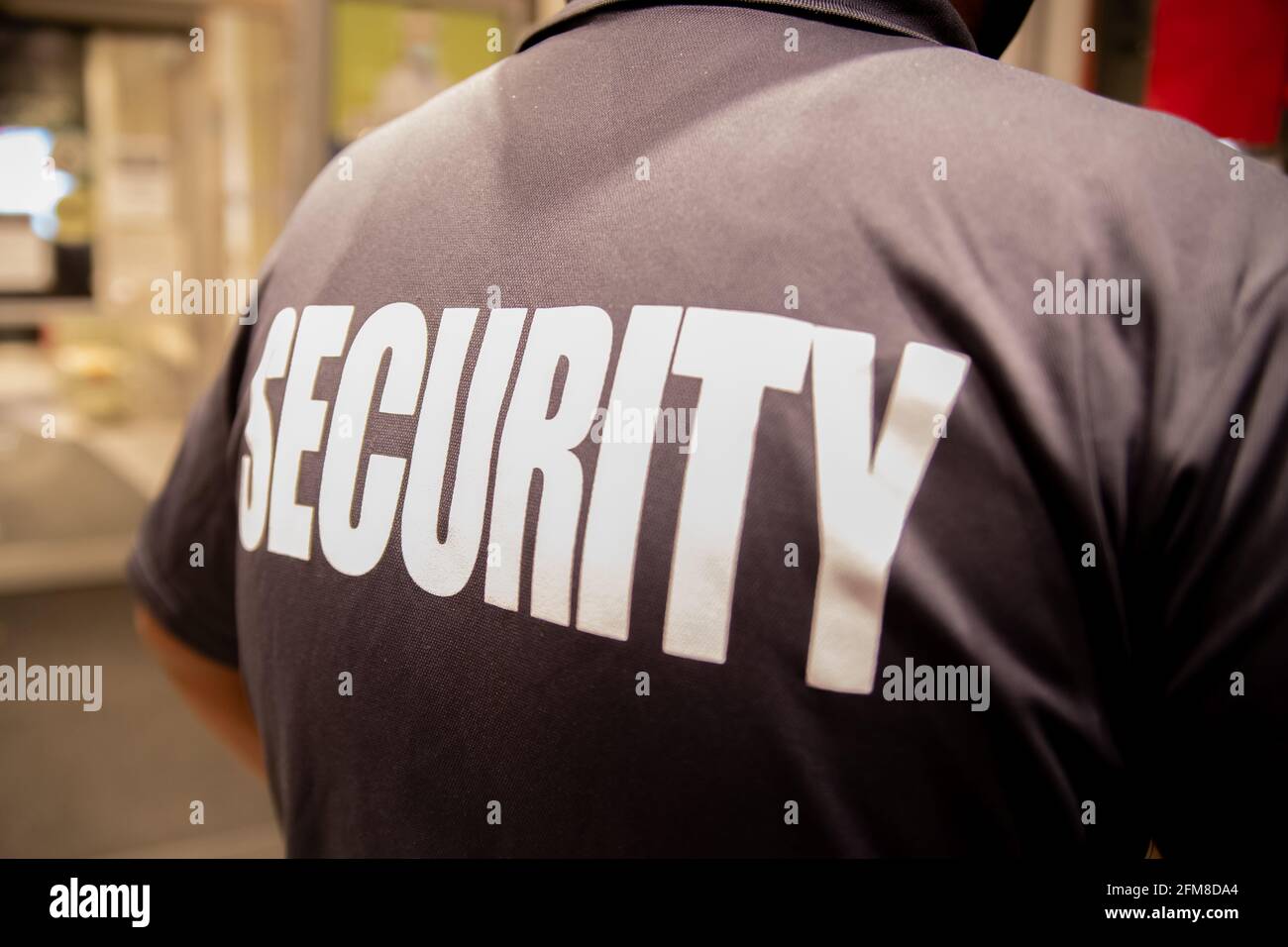 A rear view of security guard in uniform patrolling in commercial ...