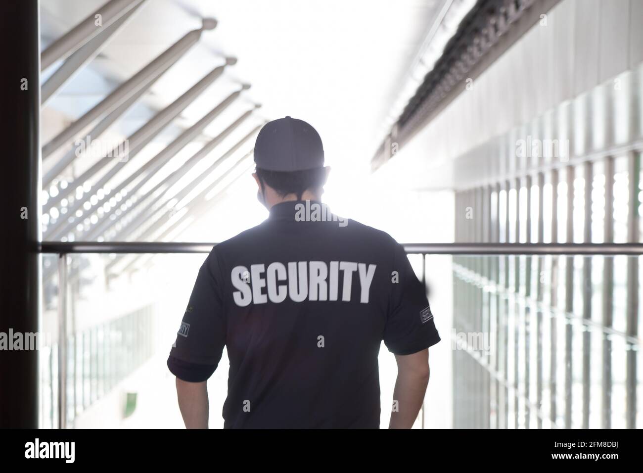 A rear view of security guard in uniform patrolling in commercial ...