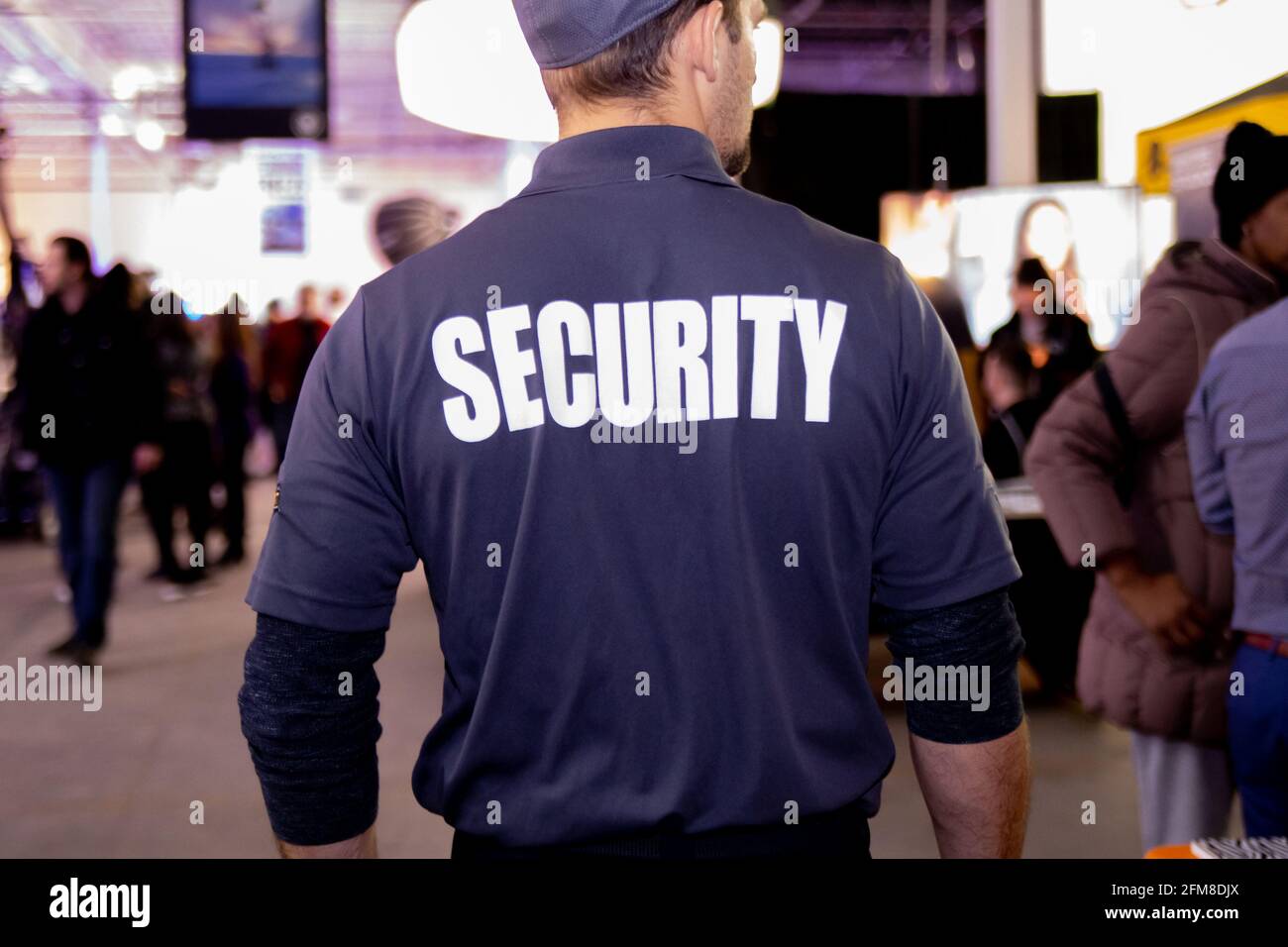 A rear view of a security guard in uniform patrolling in a commercial ...