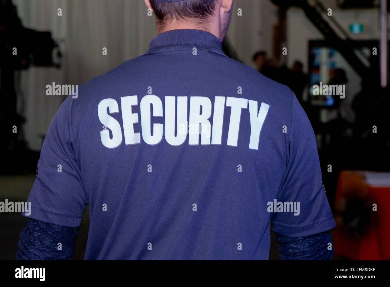 A rear view of a security guard in uniform patrolling in a commercial ...