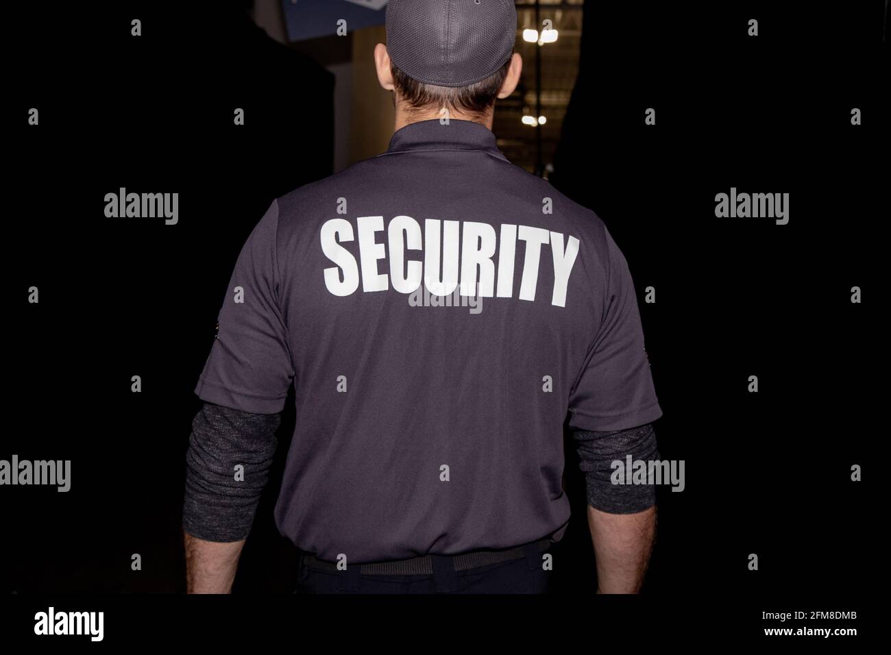 A rear view of a security guard in uniform patrolling in a commercial ...