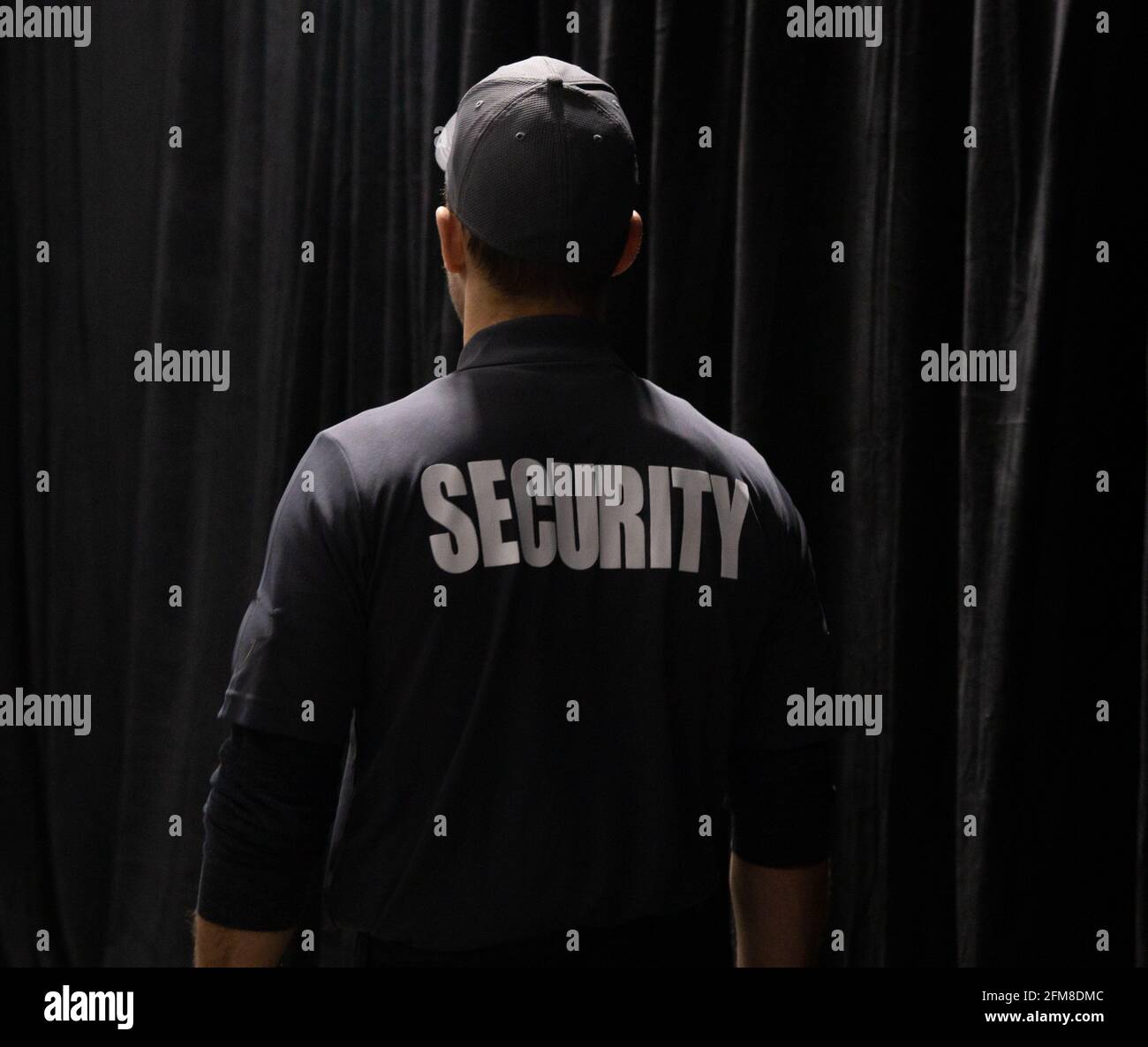 A rear view of a security guard in uniform patrolling in a commercial ...