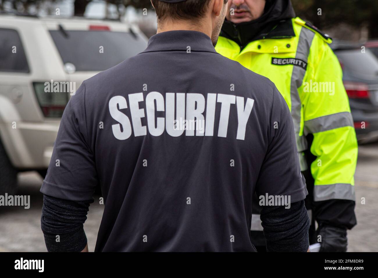 A rear view of parking security discussing plans. Security guard is ...