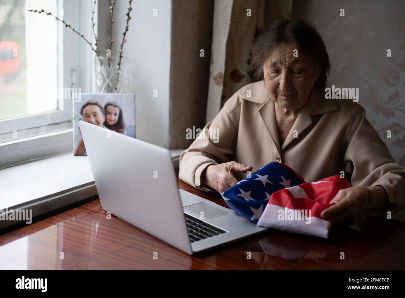Independence Day celebration after quarantine. Granny looking at laptop ...