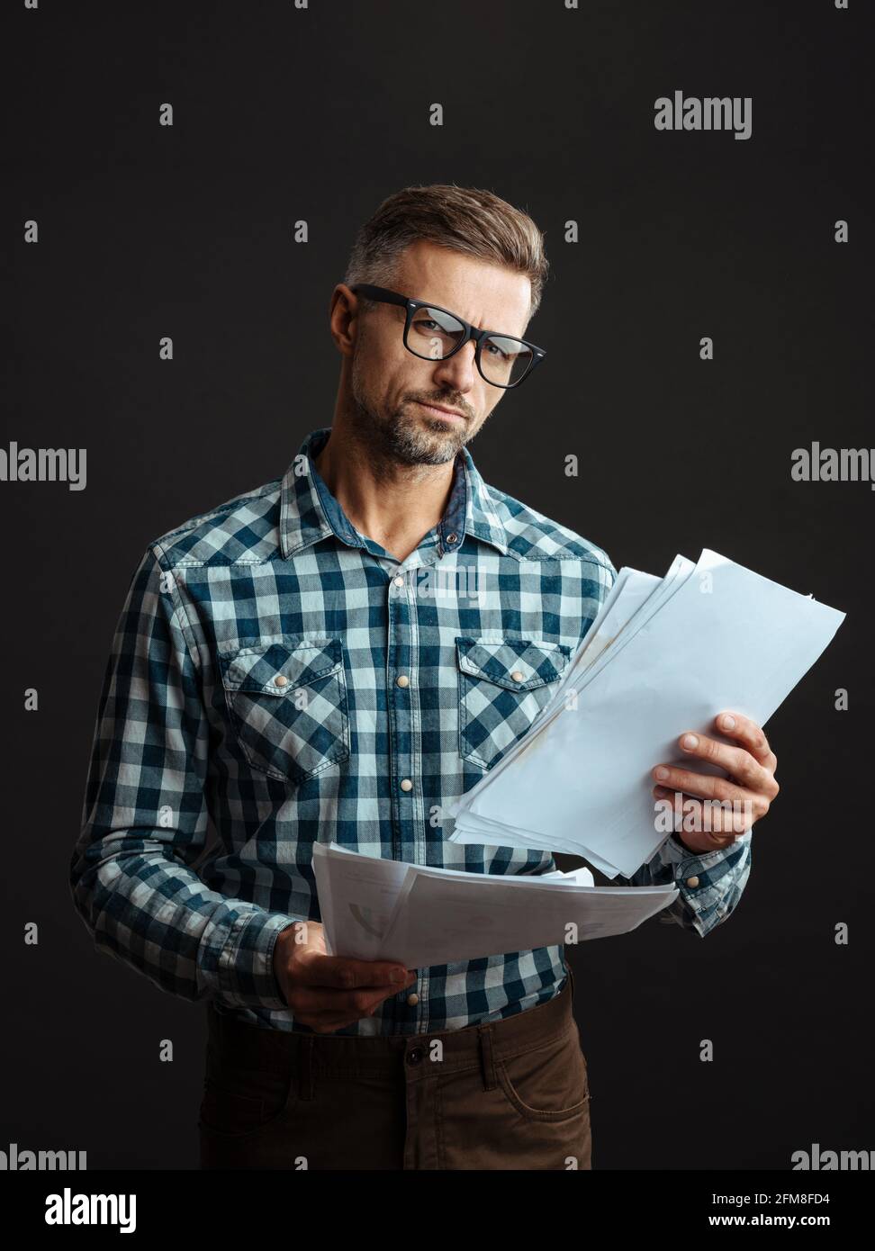 Image of a serious grey-haired man holding documents isolated over grey ...