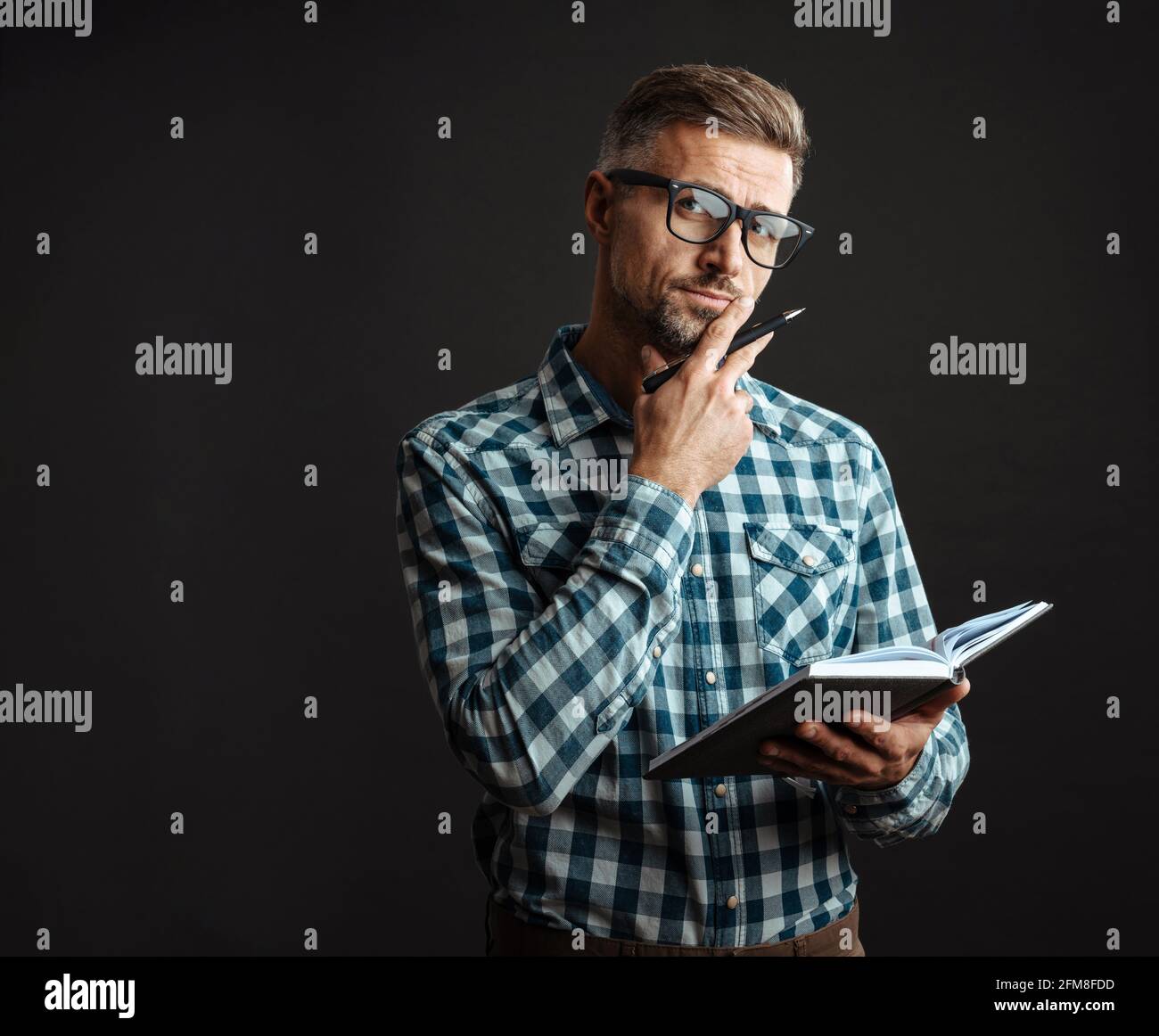 Photo of a thinking grey-haired man writing notes in notebook isolated ...