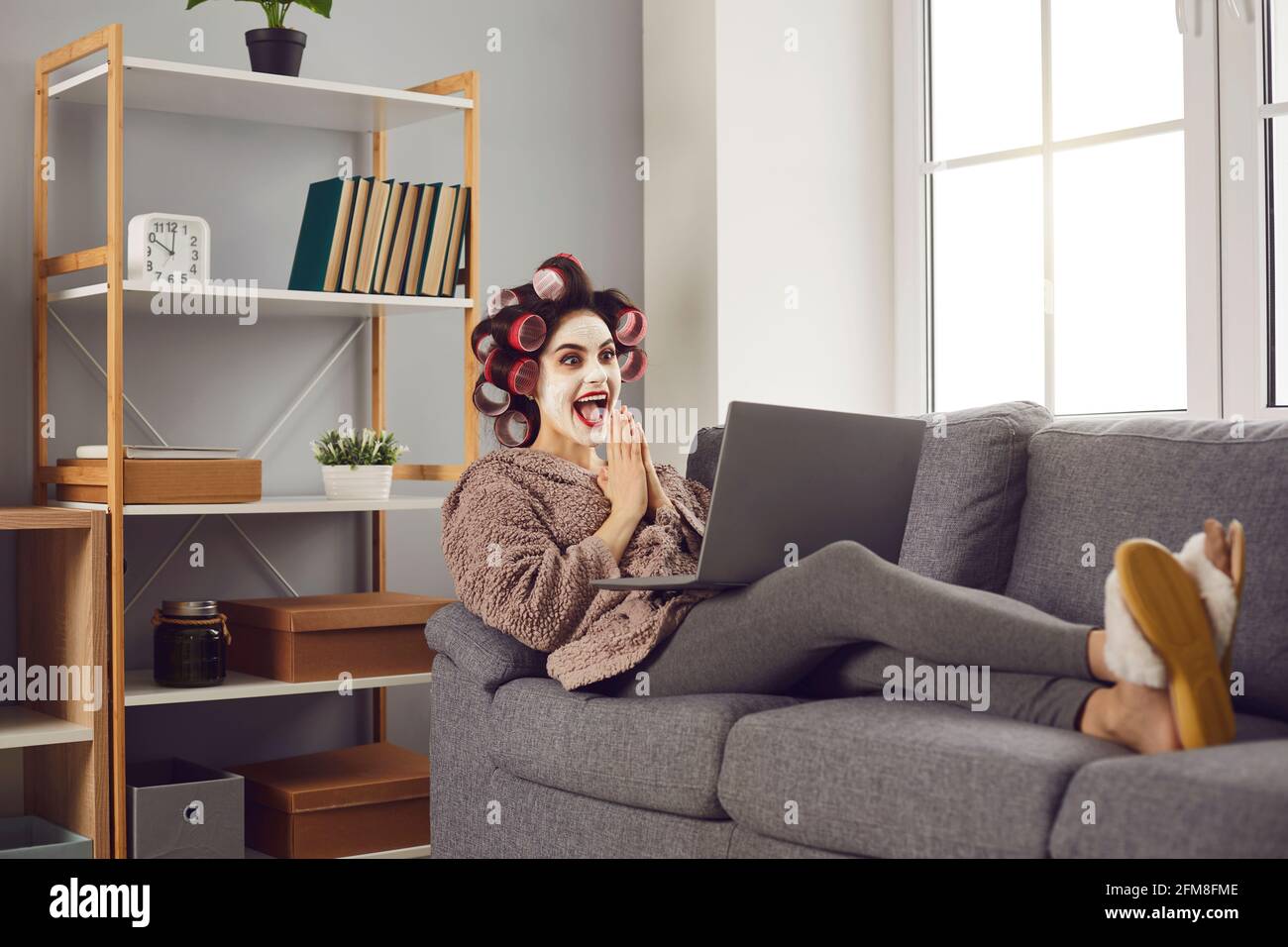 Surprised excited young woman sitting on couch and looking at her ...