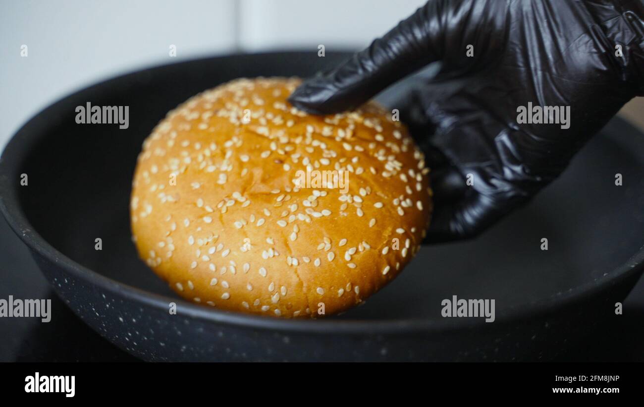 Chef in black gloves prepares bun for hamburger Stock Photo - Alamy