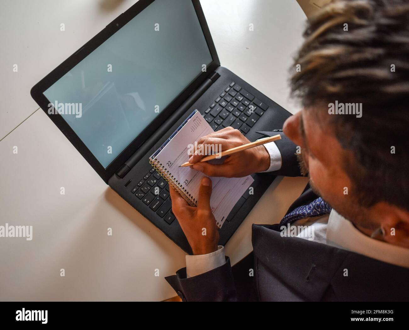 Young Spanish businessman writing his to-do list in a notepad in front ...