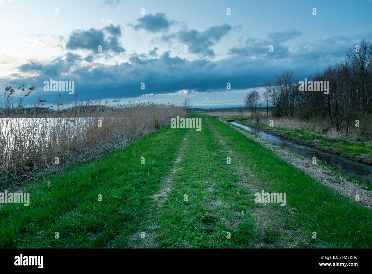 An earth embankment with a path by the Uherka river and the lake Stock ...