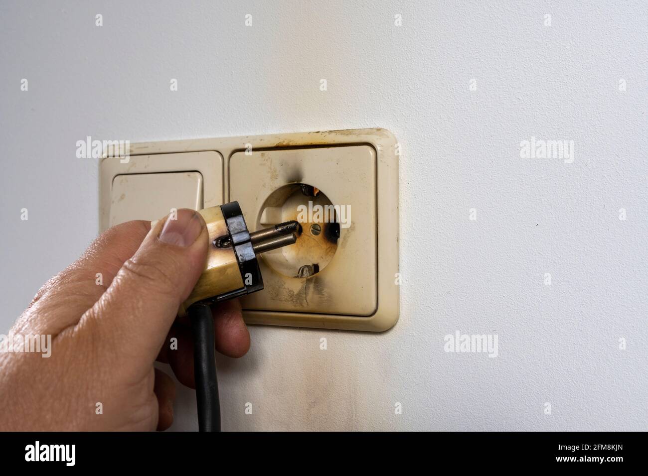 Hand Removing Plug From An Over Heated Socket Stock Photo - Alamy