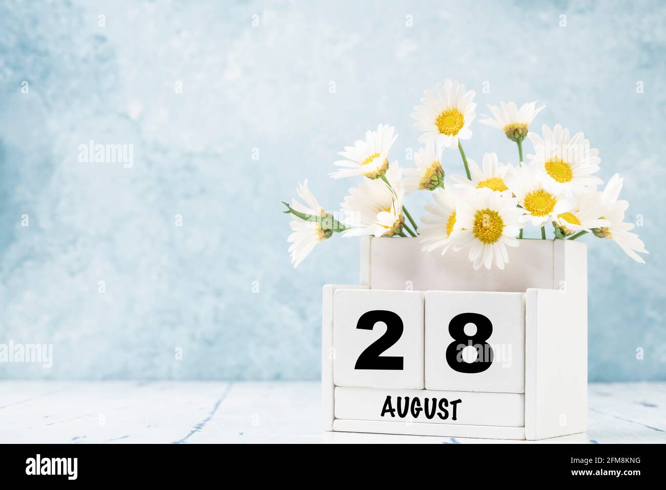 White cube calendar for August decorated with daisy flowers over blue ...
