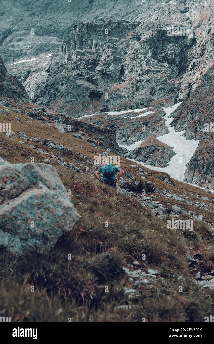 Vertical shot of a man hiking on a high rocky mountain Stock Photo - Alamy