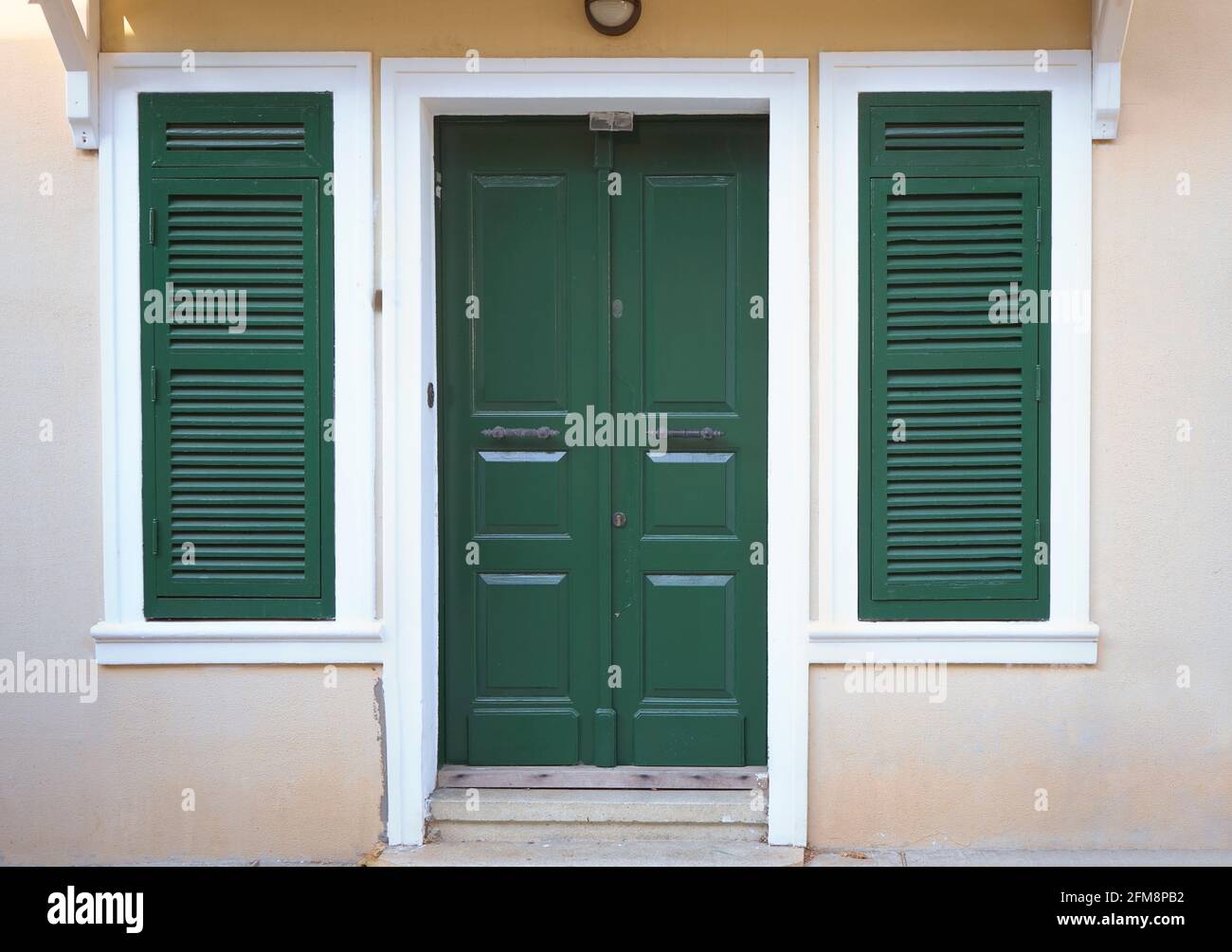 Exterior and a front door and two green wooden blinded window with ...