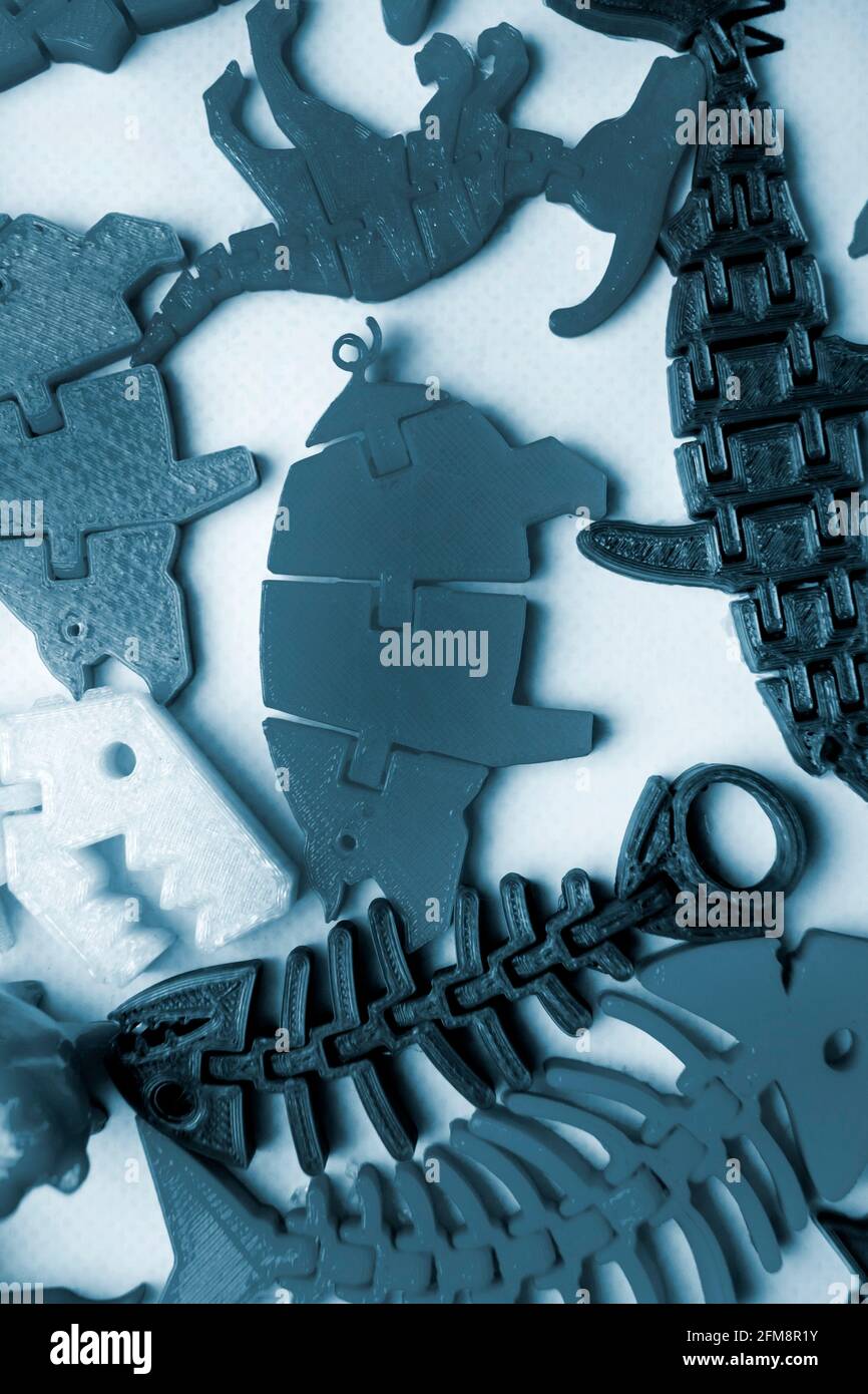 Many bright multi-colored objects printed on 3d printer lie on flat ...