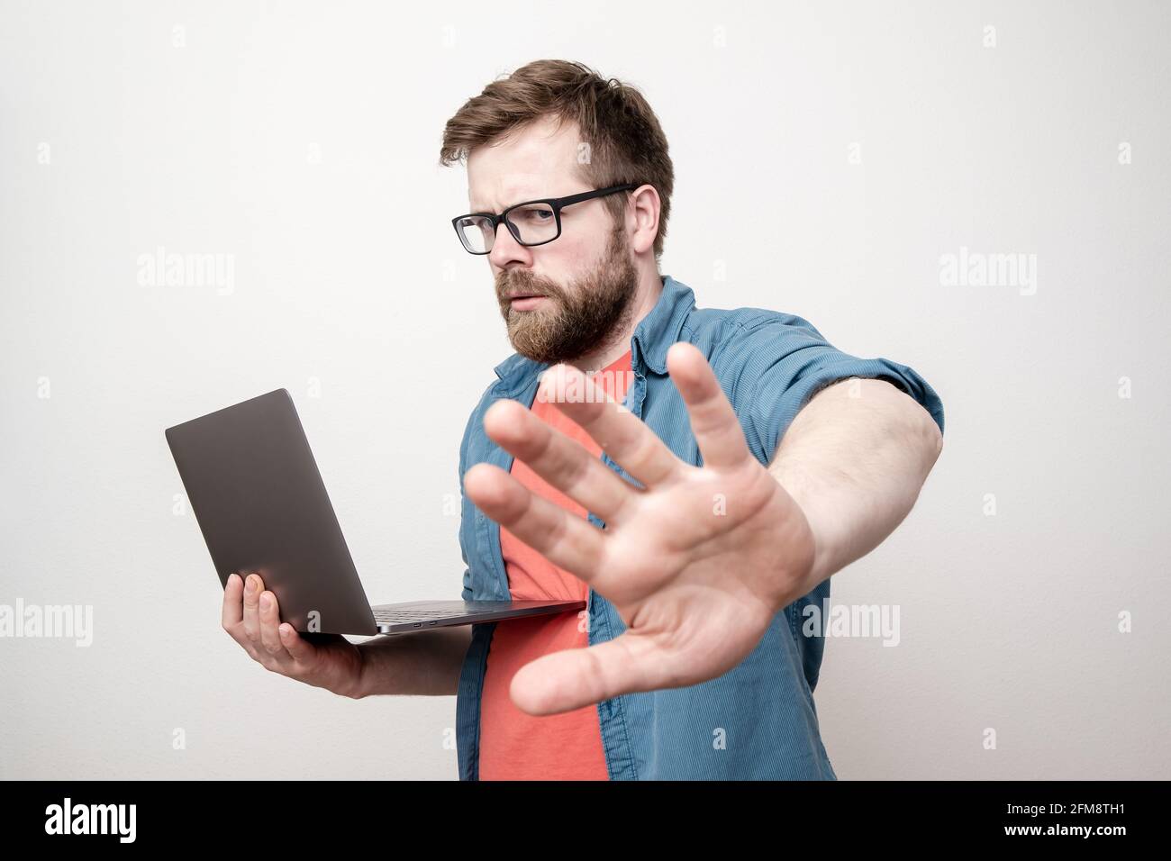 Stern man holds a laptop in one hand, and puts the other forward ...