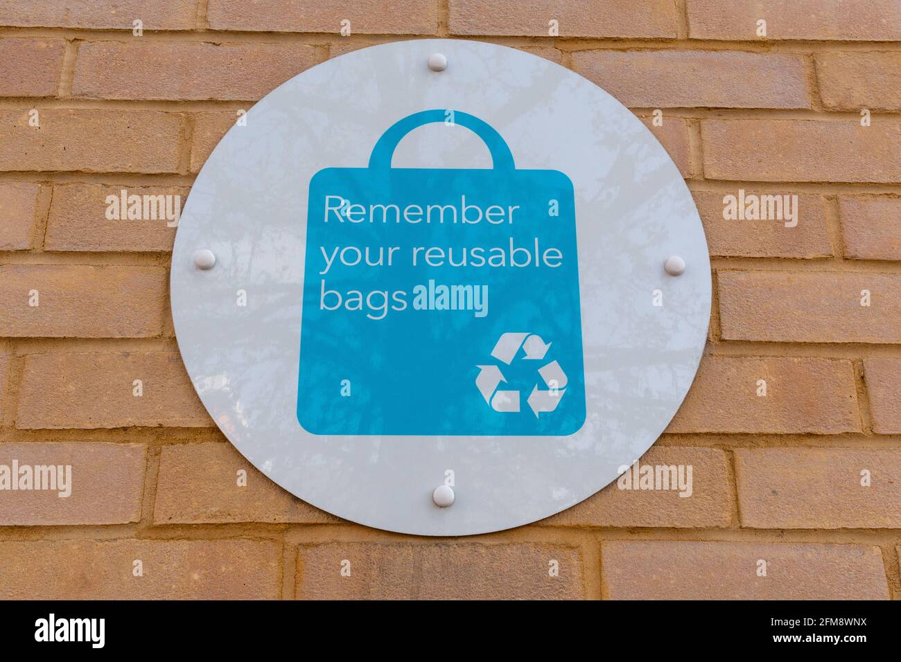 A sign reminding shoppers to bring their own reusable bags on the wall ...