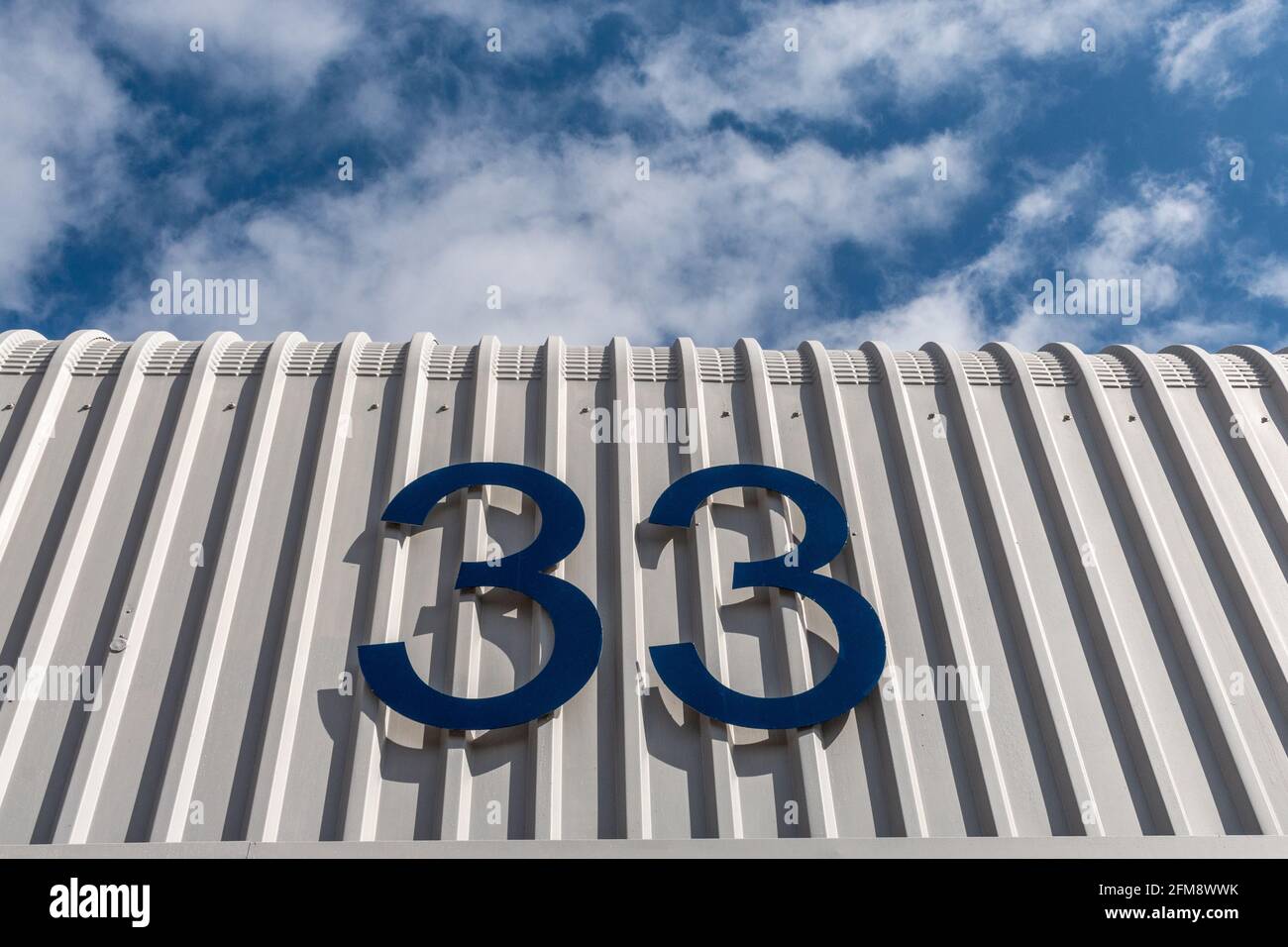 A large blue number 33 on a striped background with blue skies Stock ...