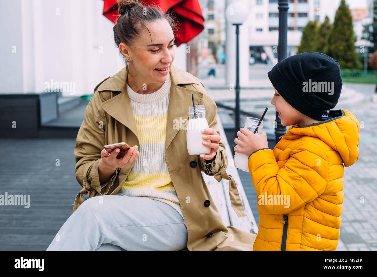 Young mom and son have fun and drink milkshake outdoors Stock Photo - Alamy