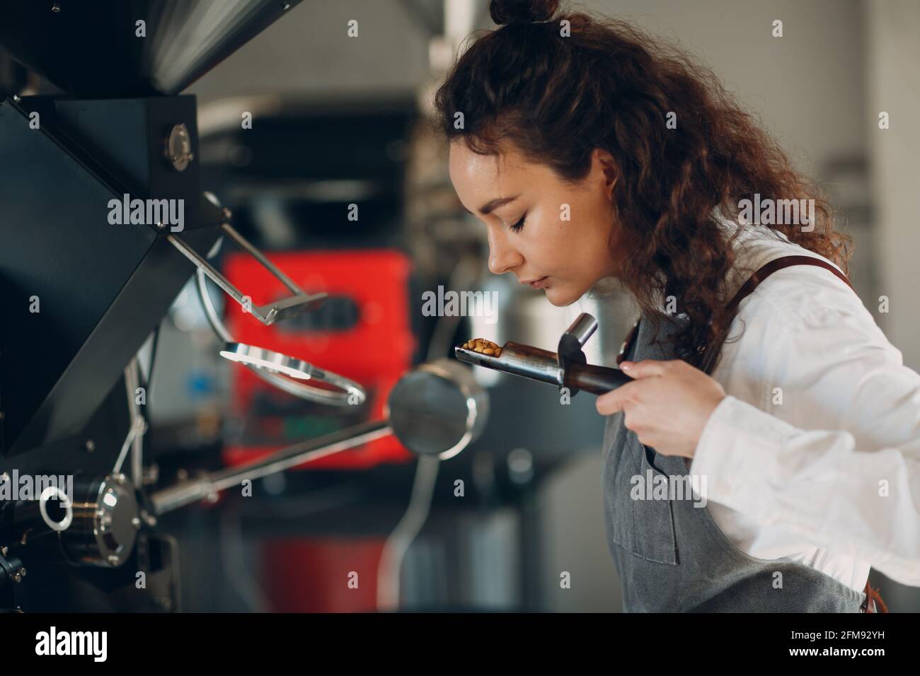 Coffee roaster machine and barista woman smell with tryer at coffee ...