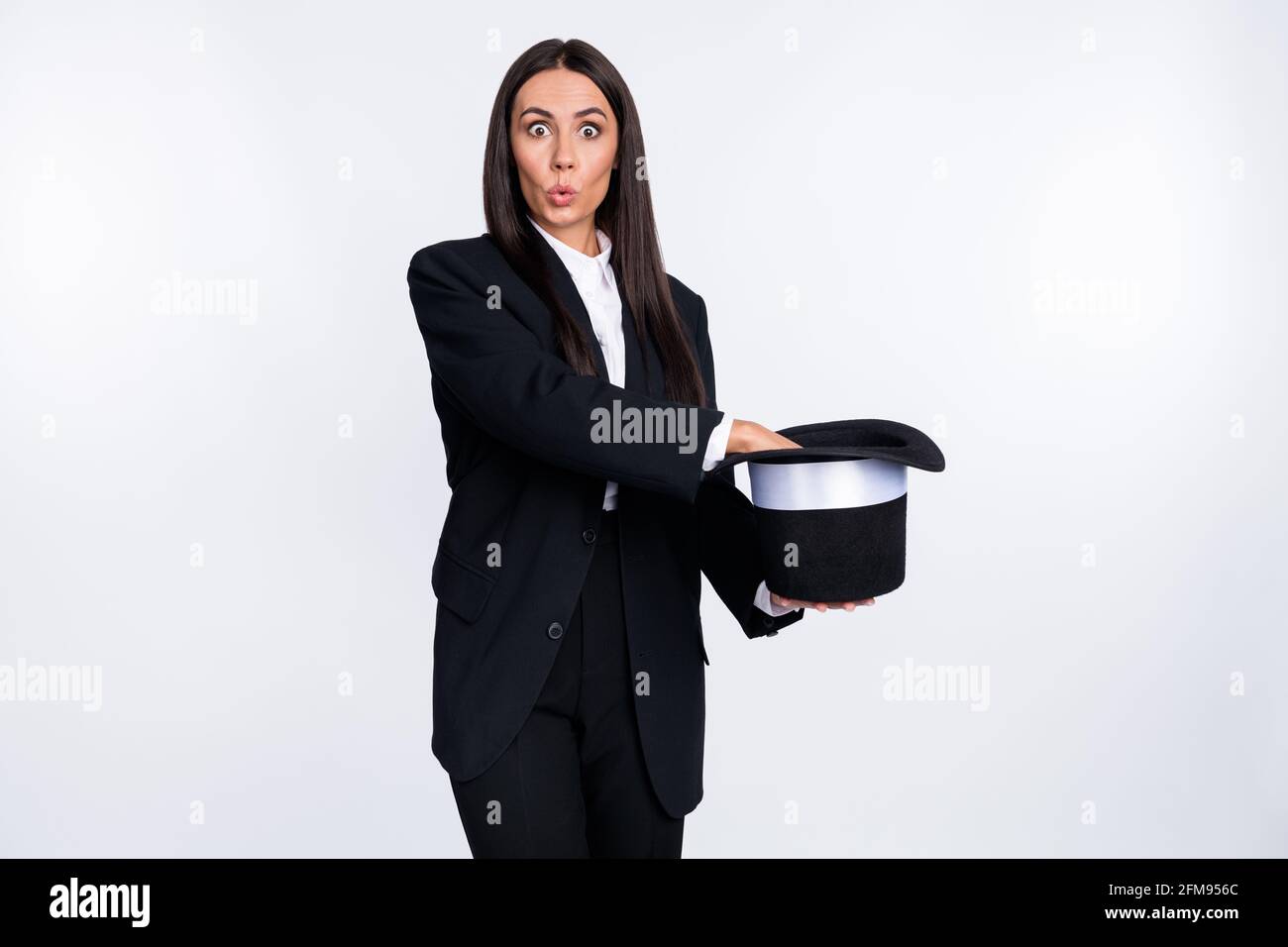 Photo of young beautiful shocked amazed girl magician doing cylinder ...