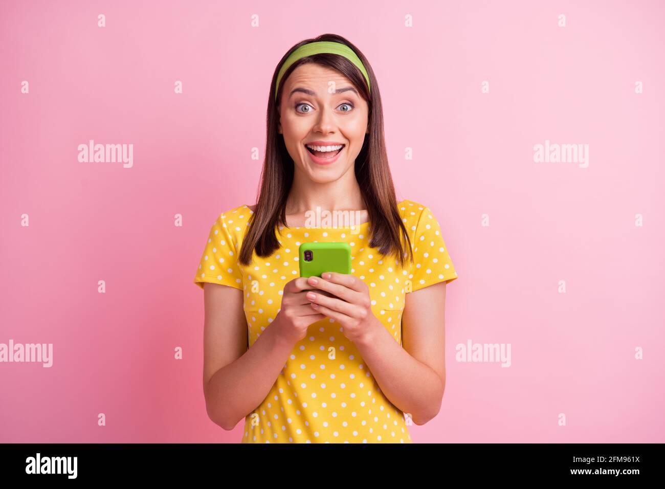 Portrait of impressed pretty brunette girl typing telephone wear yellow ...