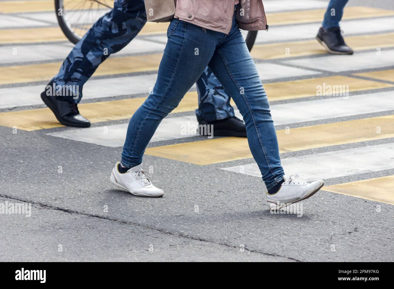 pedestrians cross the street at a pedestrian crossing on spring day ...