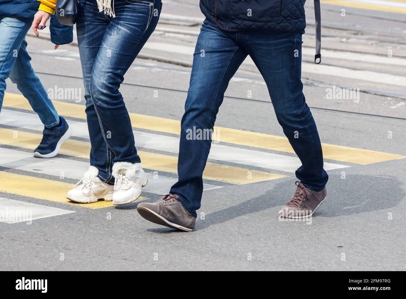 pedestrians cross the street at a pedestrian crossing on spring day ...