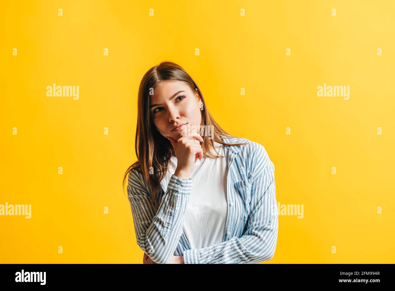 Portrait of pensive young woman in thinking moment. isolated on yellow ...