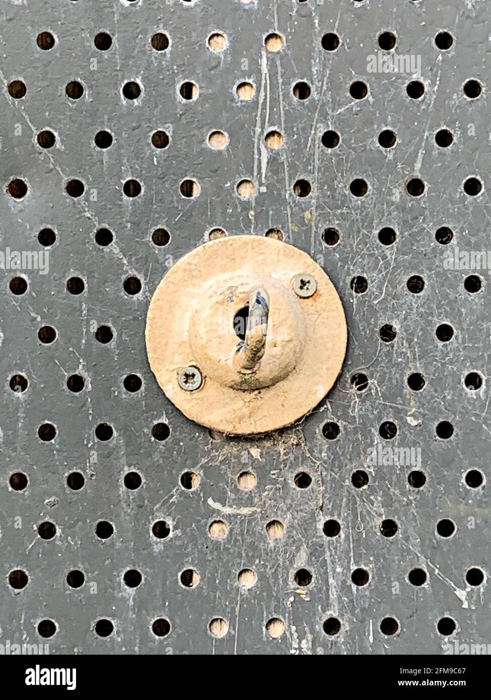 Painted metal hook fixed to perforated security screen on building ...