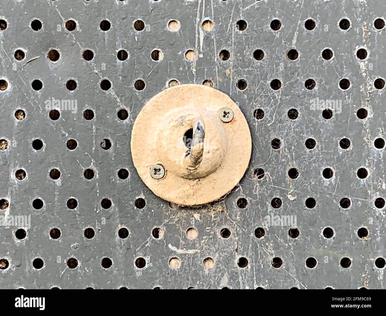 Painted metal hook fixed to perforated security screen on building ...