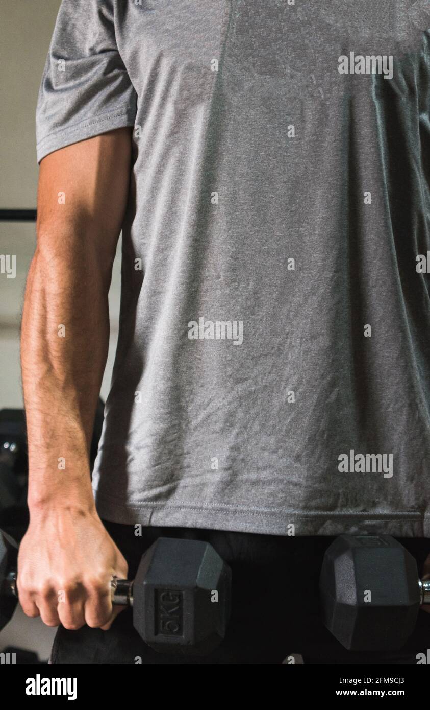 Close-up of a muscular arm holding dumbbell in a gym Stock Photo - Alamy
