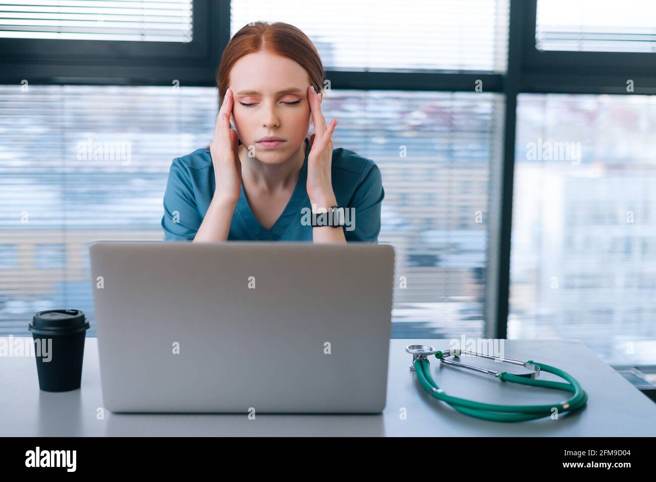 Close-up face of exhausted tired young female doctor in blue green ...