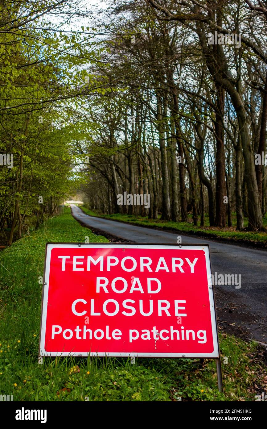 Sign saying temporary road closure pothole patching on a rural road in ...