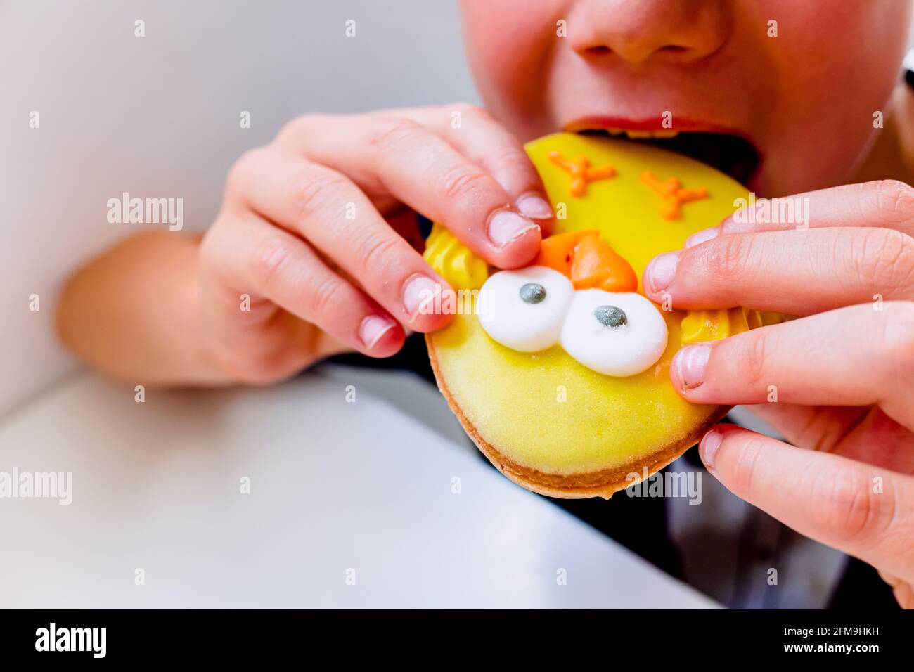 Boy bites his teeth into a cookie with icing sugar Stock Photo - Alamy
