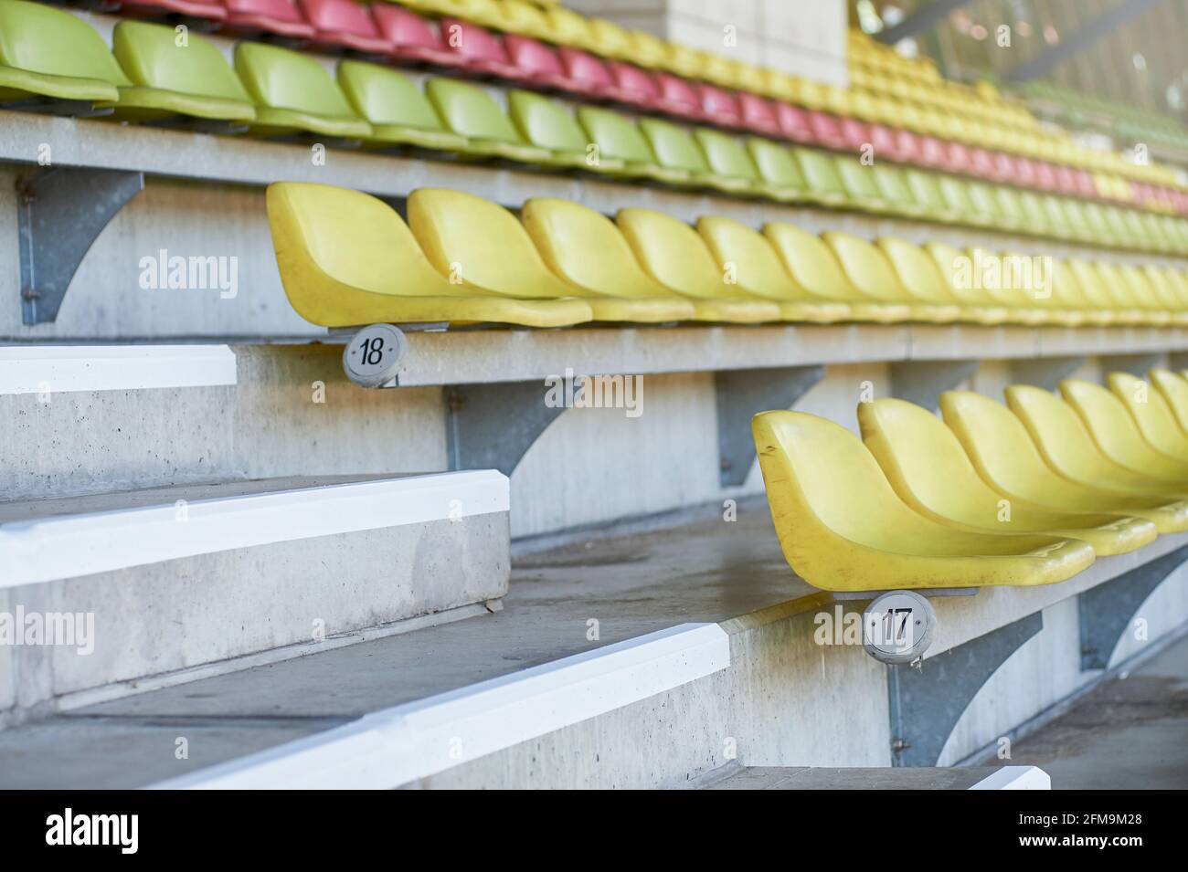 Pastel-colored, empty seat shells on the grandstand in a sports stadium ...