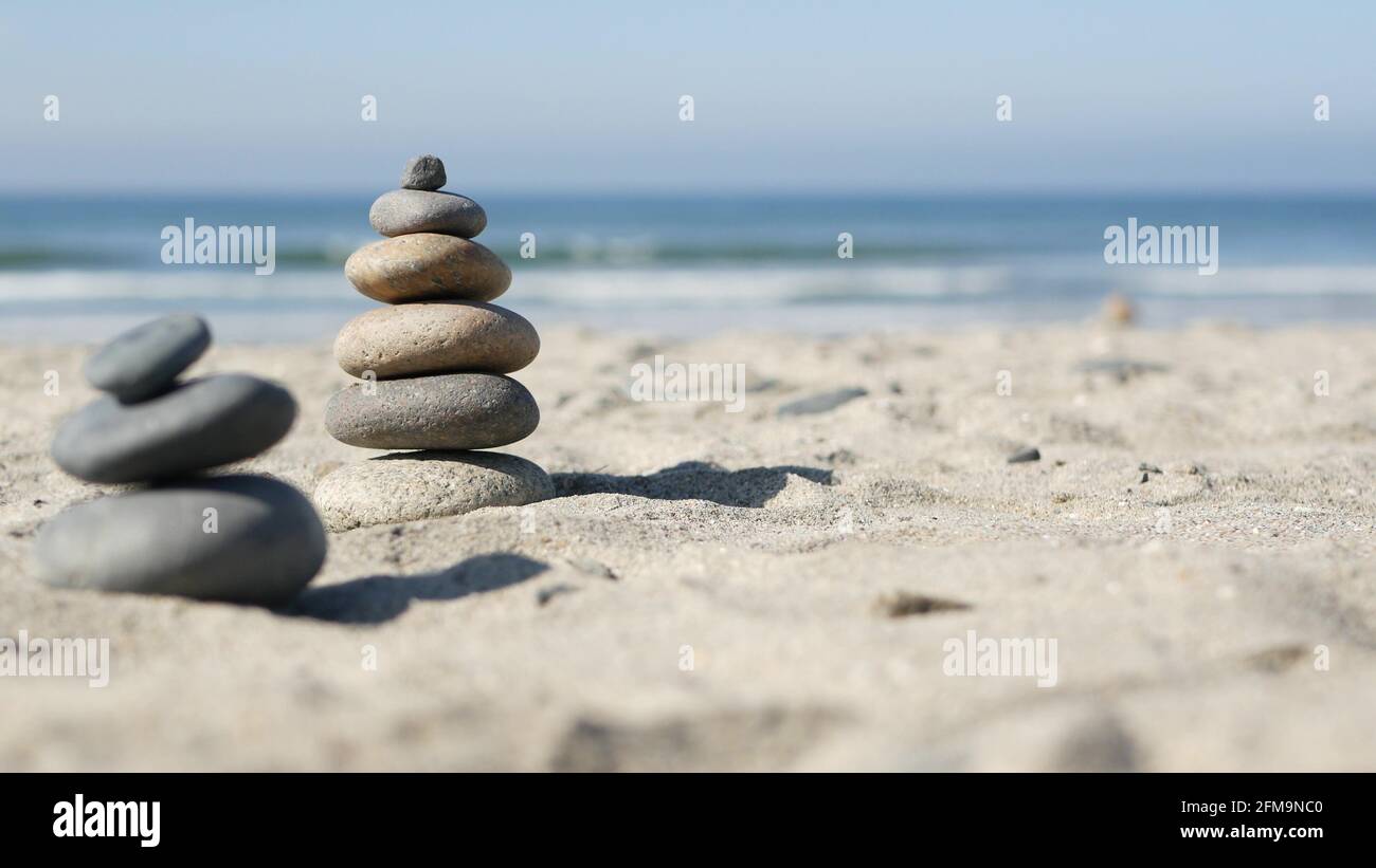 Rock balancing on ocean beach, stones stacking by sea water waves ...