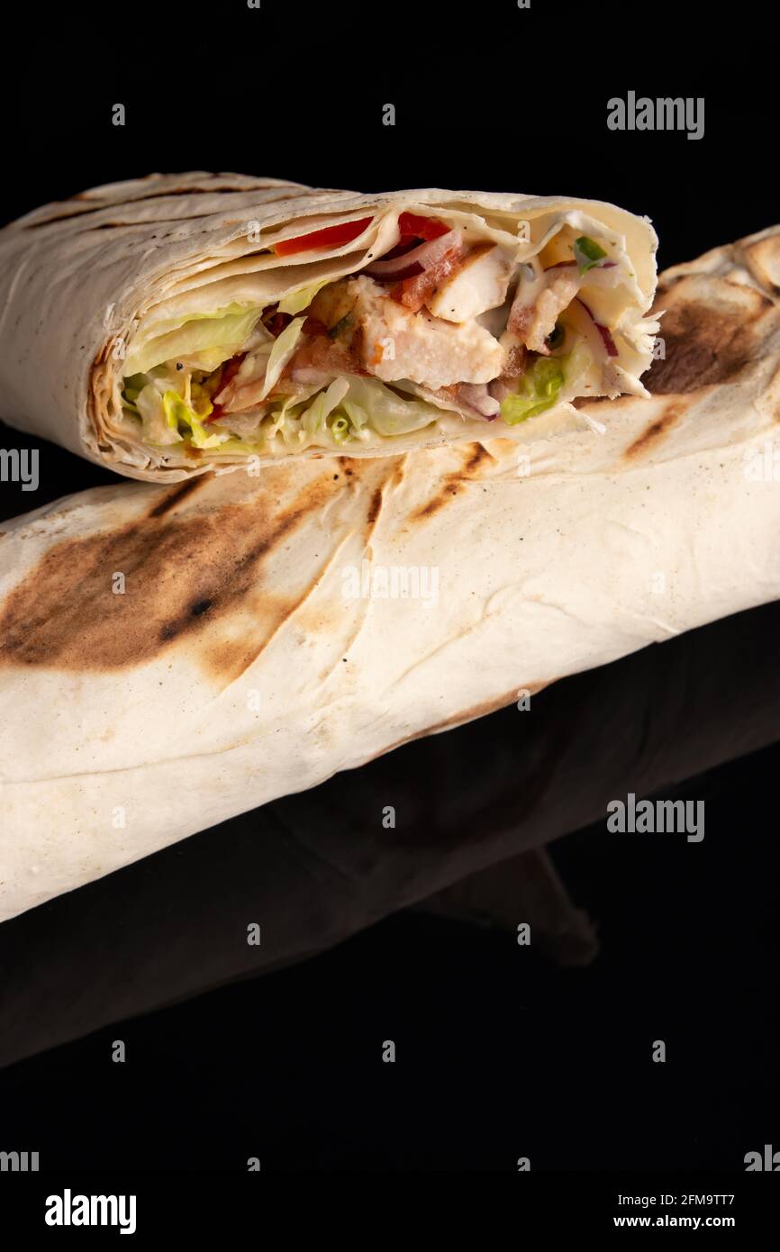 Classic shawarma kebab pita with chicken and vegetables and sauce on a ...
