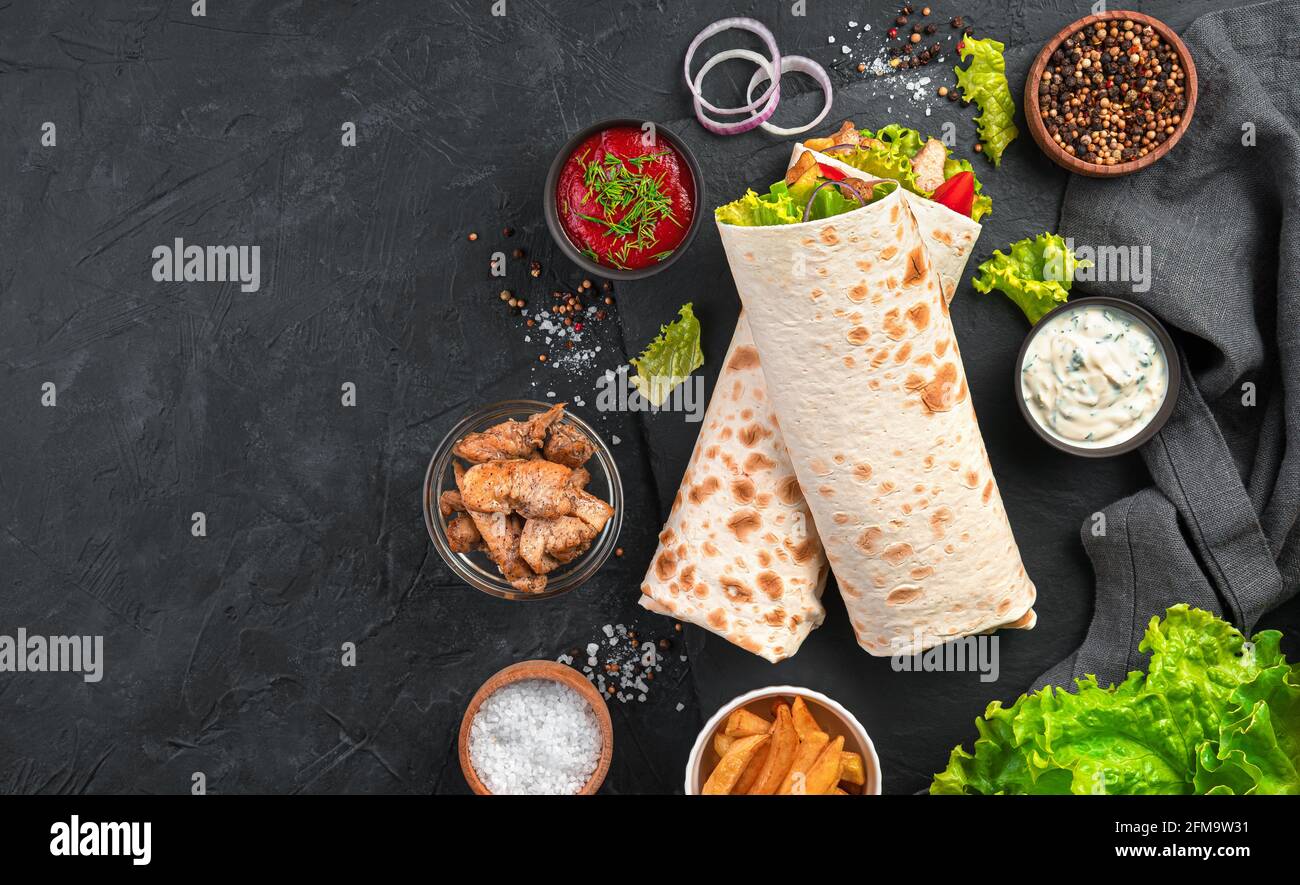 Shawarma with vegetables, salad and chicken on a black background with ...