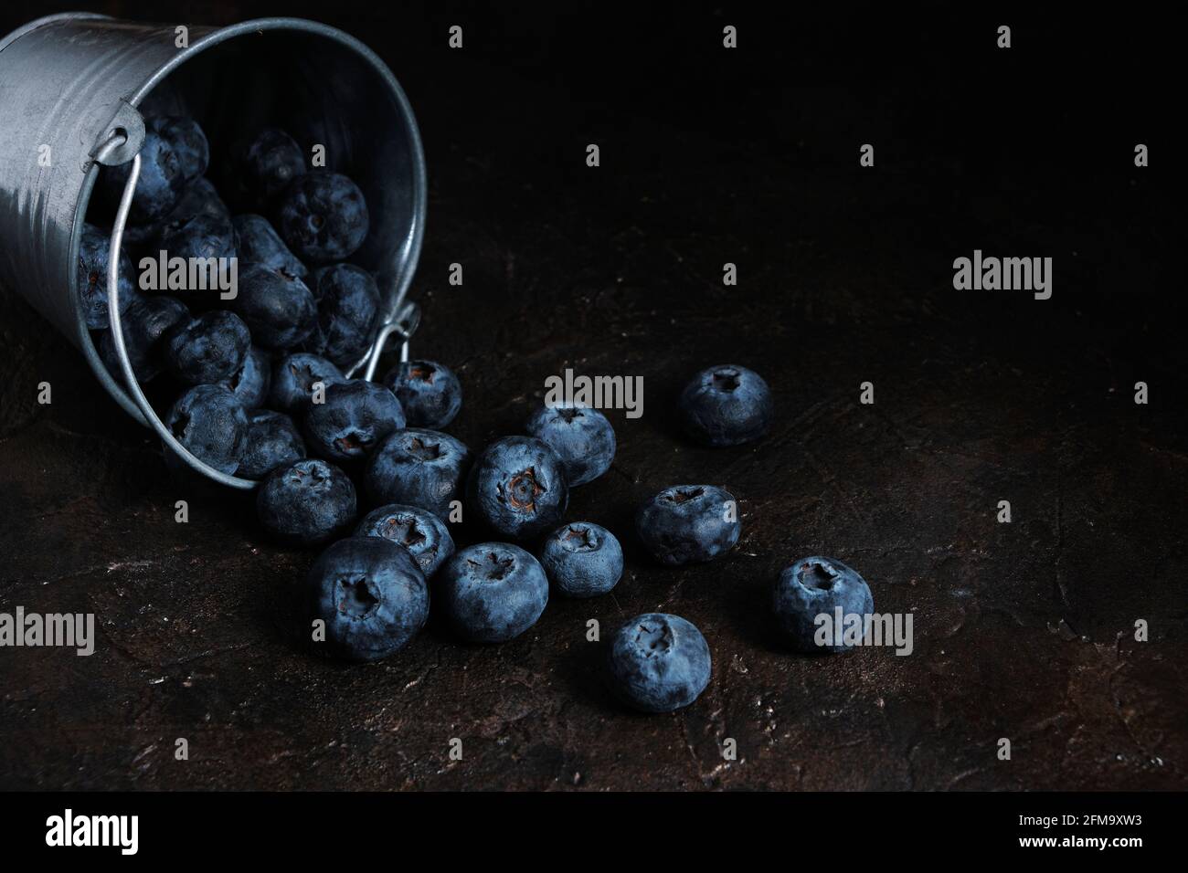 Blueberry berries spilled from metal bucket onto wooden table Stock ...