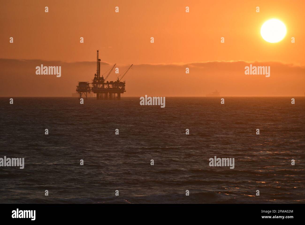 Sunset landscape with the silhouette of an offshore oil rig in ...