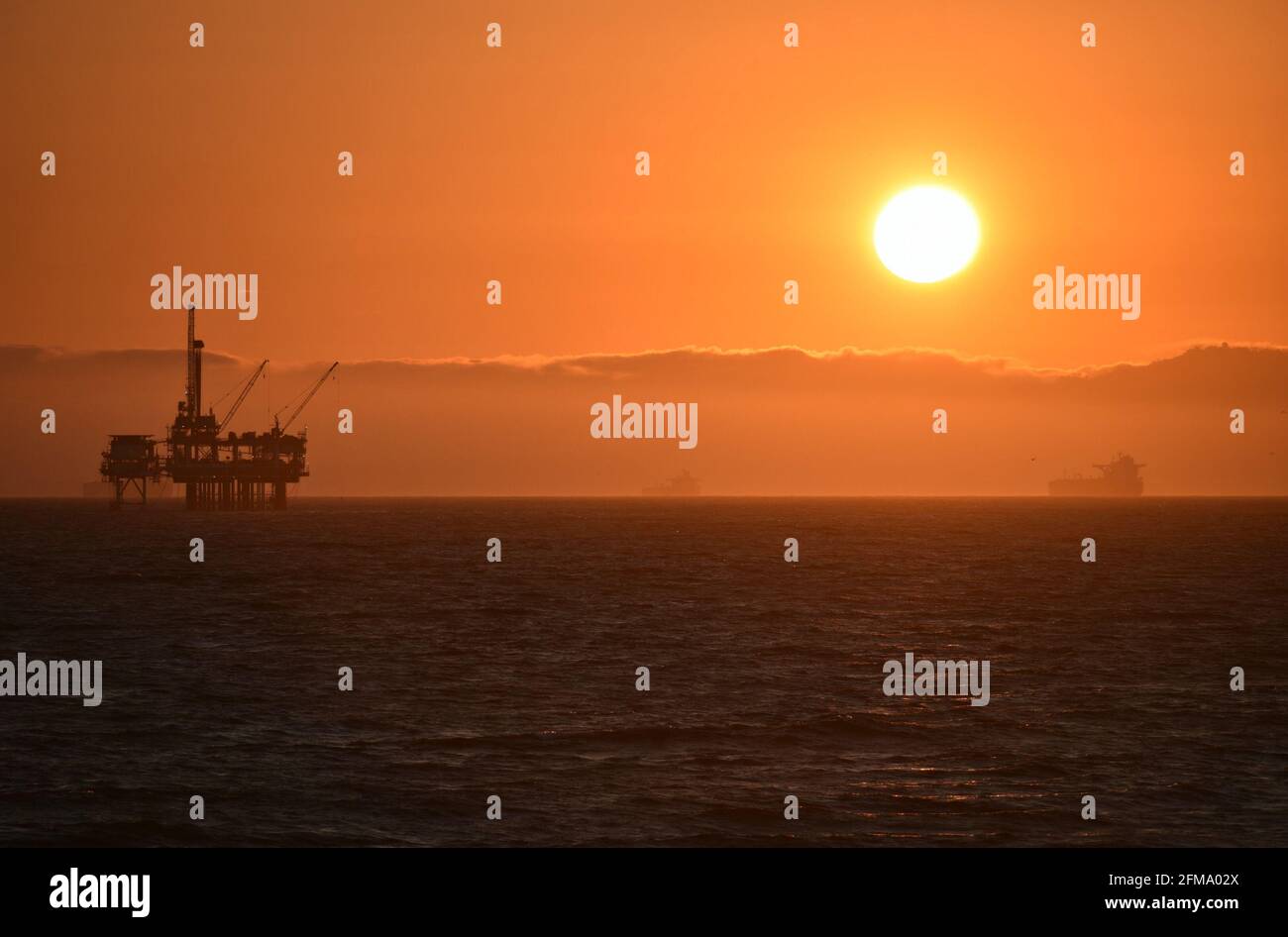 Sunset landscape with the silhouette of an offshore oil rig in ...
