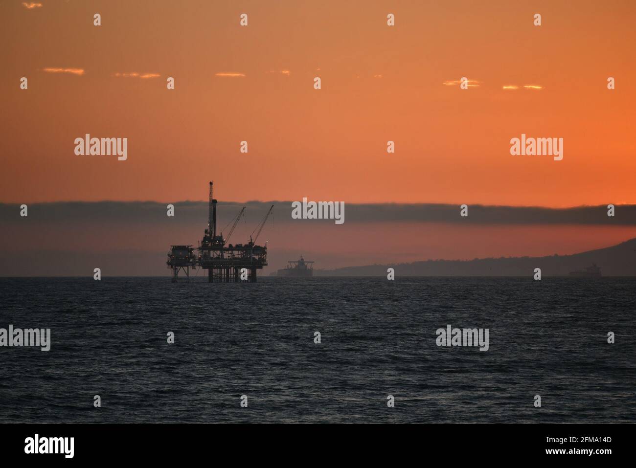 Sunset landscape with the silhouette of an offshore oil rig in ...