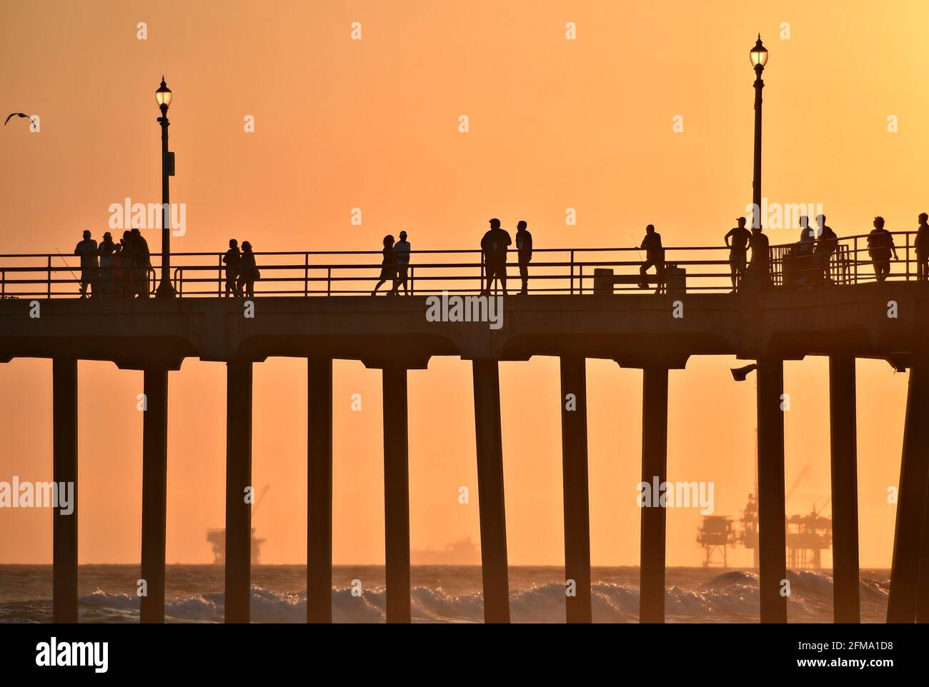 Sunset landscape with people silhouettes on Huntington Beach Pier in ...