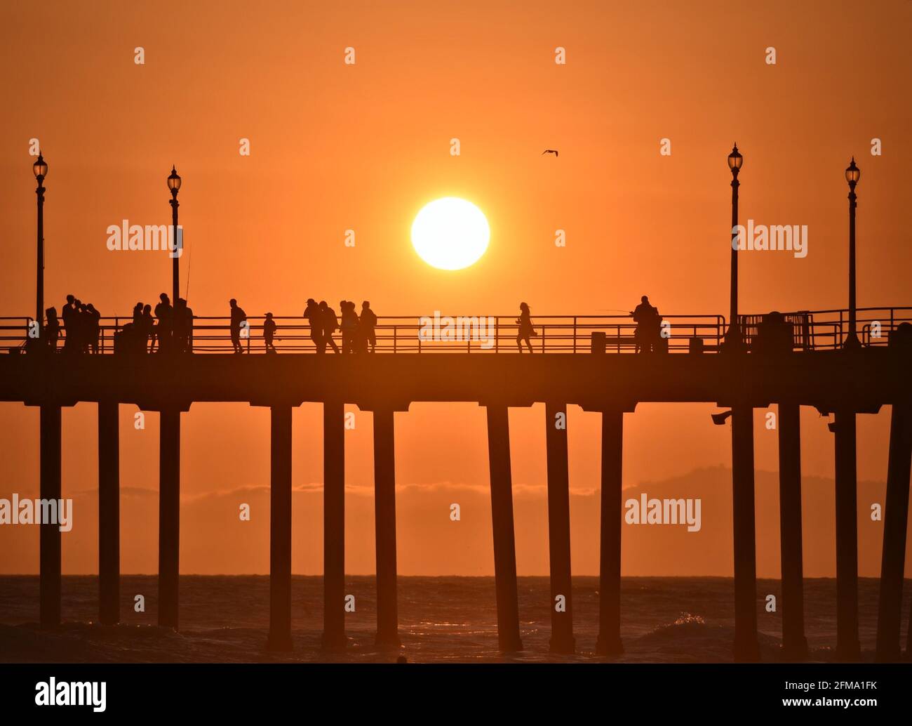 Sunset landscape with people silhouettes on Huntington Beach Pier in ...