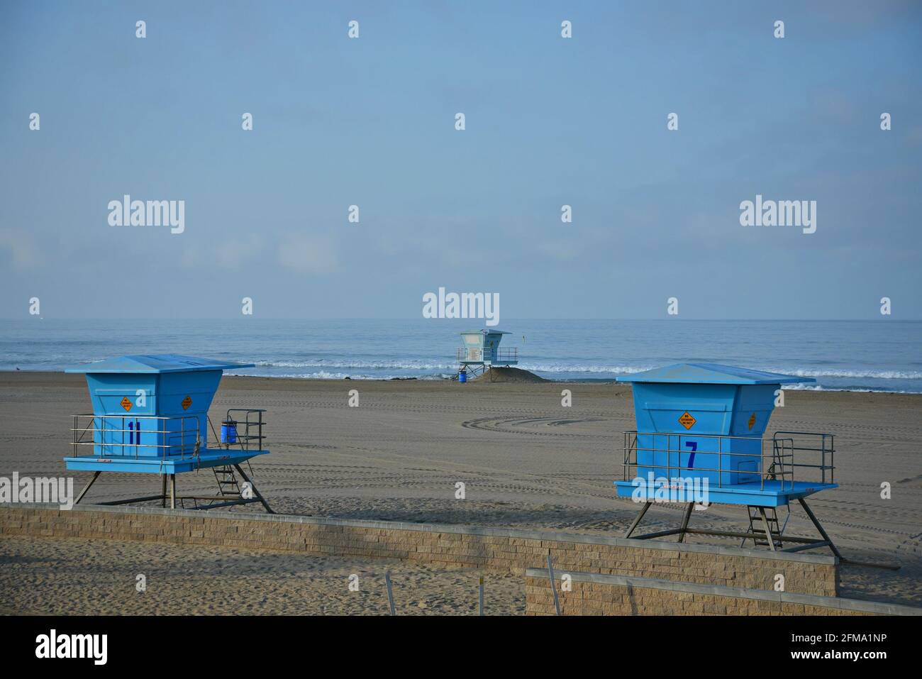 Landscape with light blue lifeguard watchtowers on the sandy shoreline ...