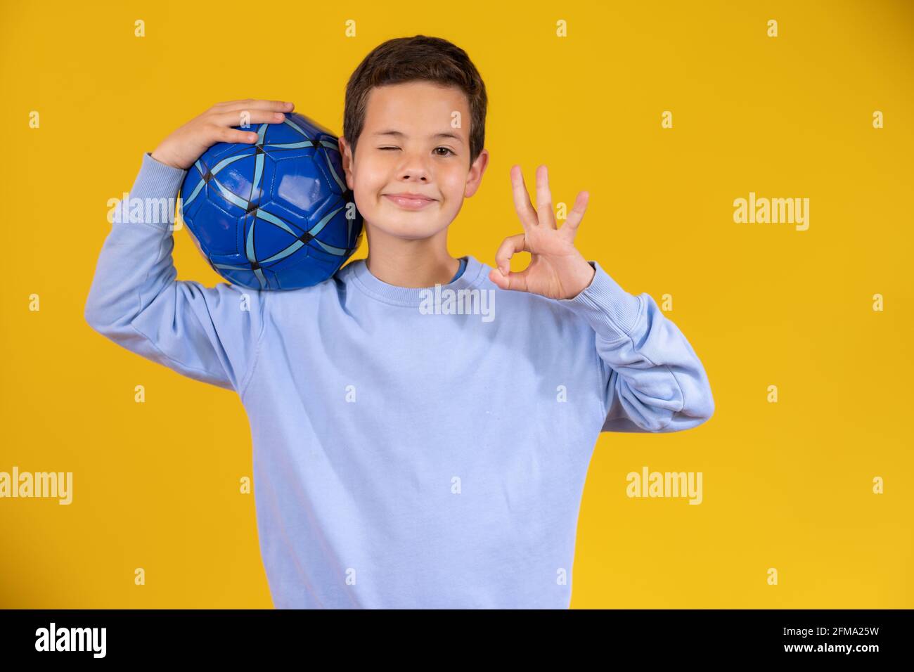 Happy boy winking with a blue ball showing thumbs up, isolated on ...