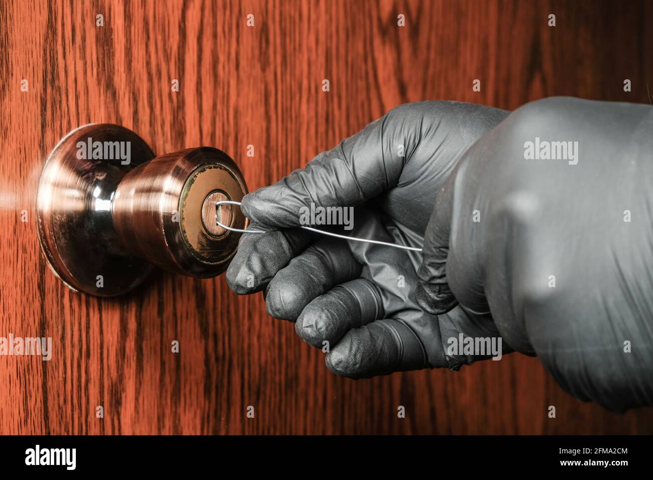 Thief in black gloves opens a wooden door with a simple lock using an ...