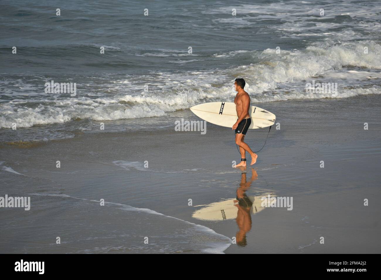 Male surfer with his surfboard on the shoreline of Huntington Beach in ...