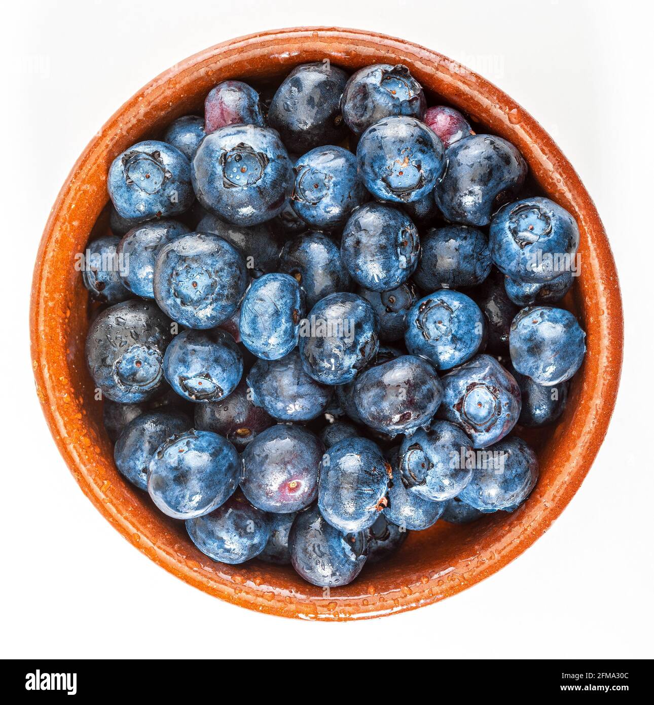 Fresh and raw blueberries with drops of water. In a clay bowl and ready ...